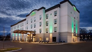 Um hotel de vários andares com entrada coberta e sinalização iluminada.