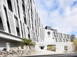 Um hotel moderno com fachada vertical, terraço no terraço e área de entrada com paisagismo.