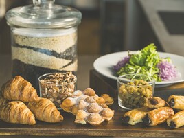 Uma mesa com doces, frutos secos e um pote de comida em camadas.