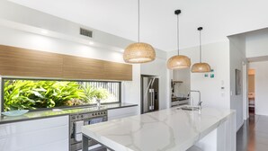 Uma cozinha moderna com uma ilha grande, eletrodomésticos de aço inoxidável e iluminação pendente.