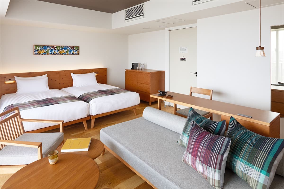 Quarto de hotel moderno com uma cama grande, um sofá, uma mesa de jantar e uma pequena cozinha.