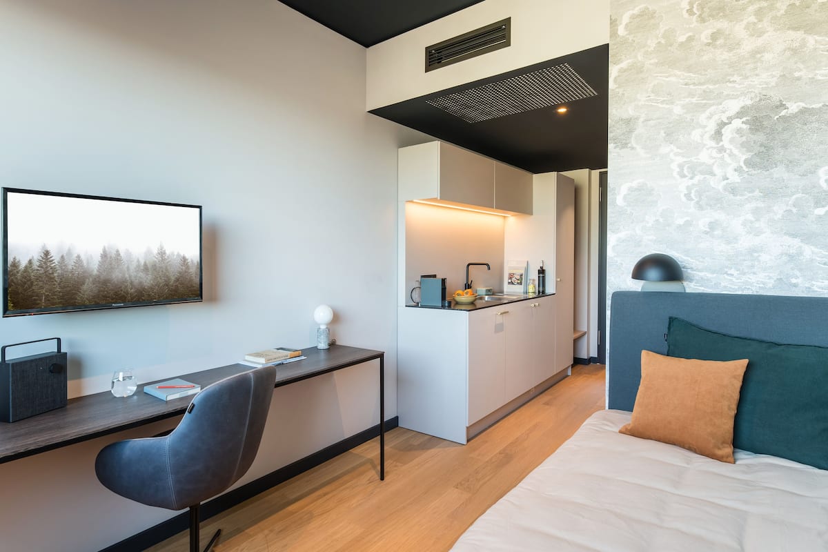 Quarto de hotel moderno com escrivaninha, cadeira e cama.