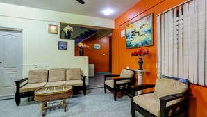 Uma área de recepção com sofá, cadeiras, uma mesa e um quadro na parede.