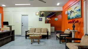 Uma sala de estar com sofá, poltronas, mesa de centro e televisão em prateleira de vidro.
