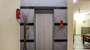 Um elevador com visor digital, extintor de incêndio e planta decorativa.