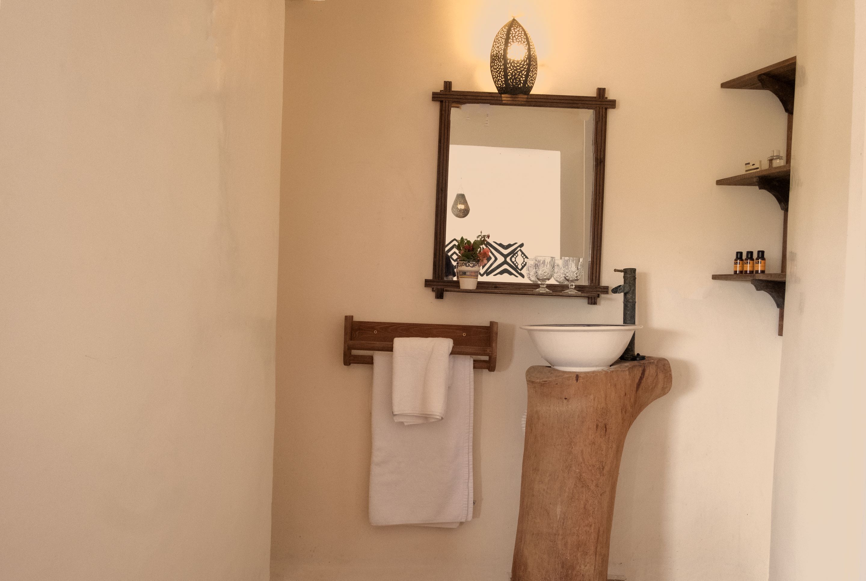 Casa de banho com toucador de madeira, lavatório branco, espelho e porta-toalhas.