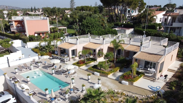 Vista aérea de um resort com piscina, espreguiçadeiras e um jardim bem cuidado.