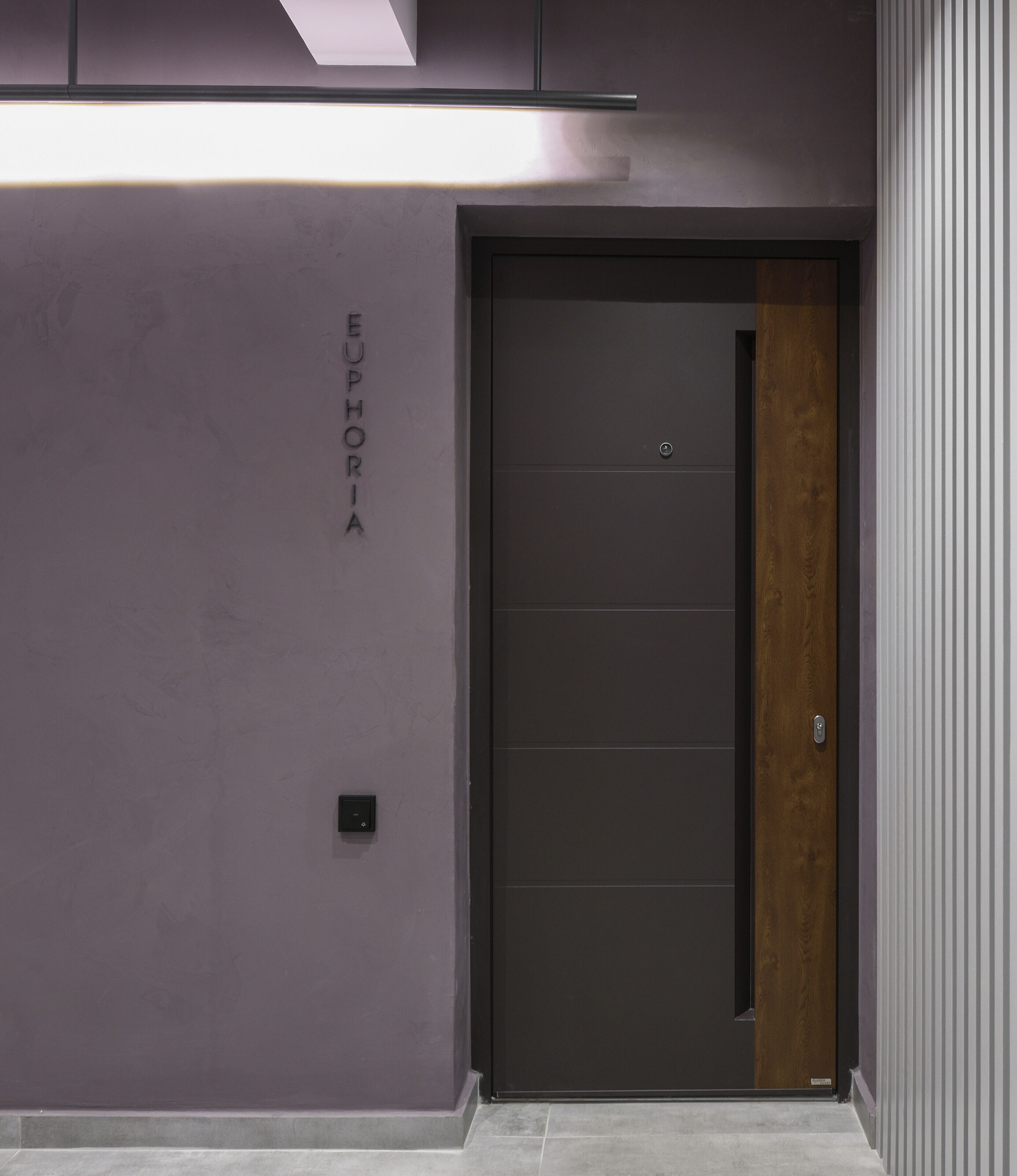 Um elevador moderno com porta escura e painel de madeira.