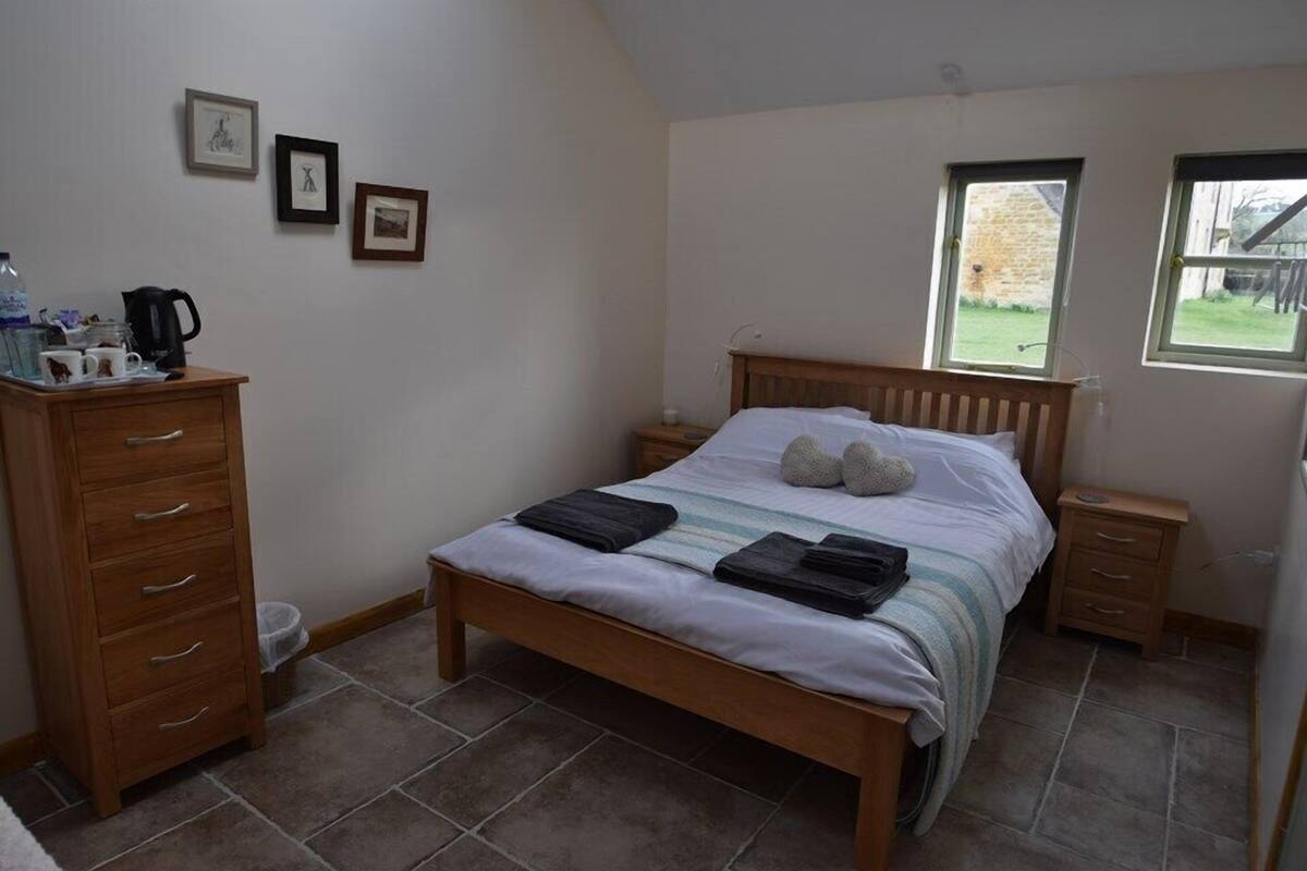 Um quarto com cama de madeira, mesas de cabeceira, cômoda e quadros nas paredes.