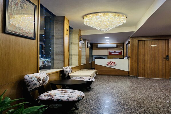 Um hall de hotel com balcão de recepção, área de estar e um candelabro.