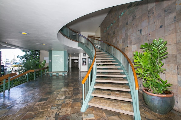 Uma escadaria curva com corrimãos de madeira e um vaso de planta ao lado.