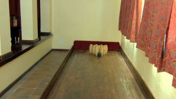Quarto com piso de madeira, ventilador de teto, cortinas vermelhas e parede revestida de azulejos.