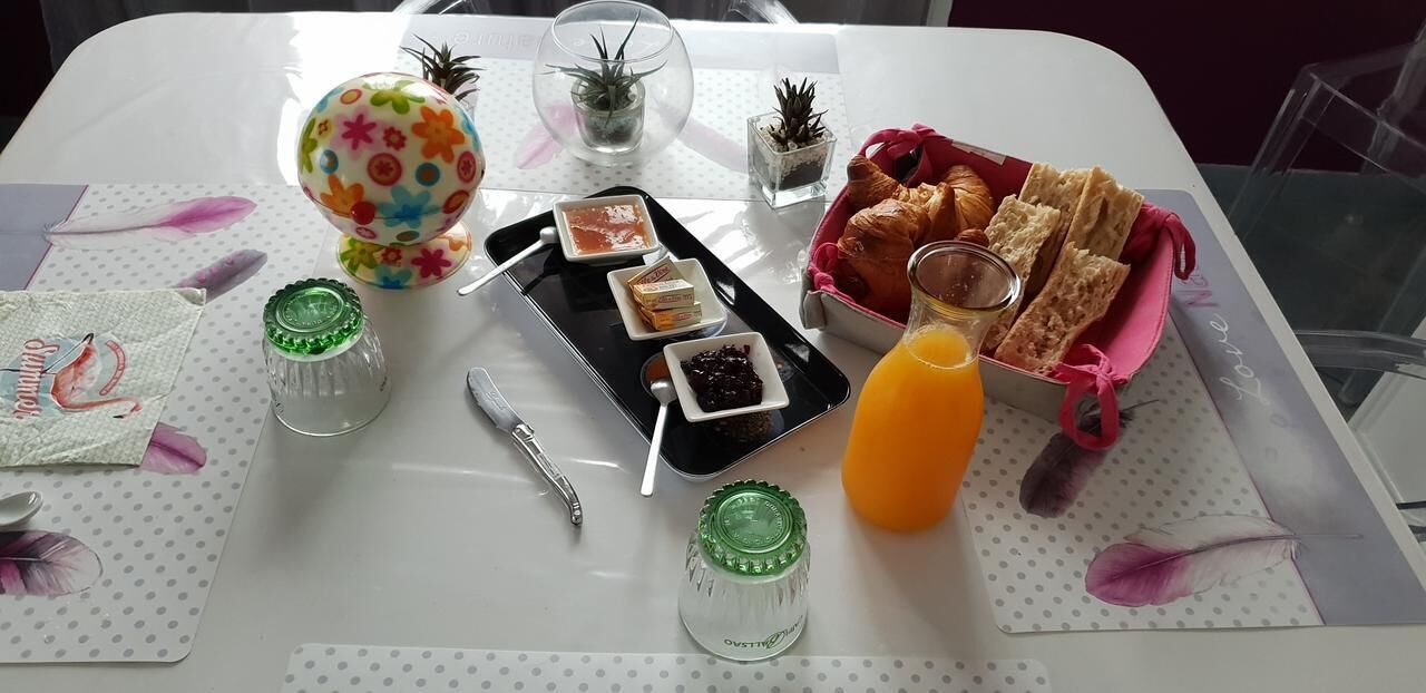 Mesa de café da manhã com croissants, doces, um copo de suco de laranja e acompanhamentos.