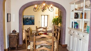 Uma sala de jantar com mesa e cadeiras de madeira, teto em arco e lustre.