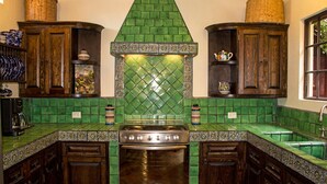 Cozinha com painel de azulejos verdes, armários de madeira e fogão de aço inoxidável.