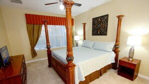 Uma cama de dossel com estrutura de madeira, uma mesa de cabeceira com abajur e uma janela com cortinas.