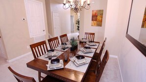 Uma sala de jantar com uma mesa de madeira posta para seis pessoas, rodeada por seis cadeiras de madeira.