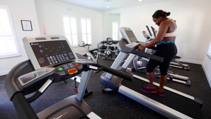 Academia com esteiras, bicicleta ergométrica e aparelho de musculação.