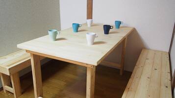 Uma mesa de madeira com quatro chávenas e dois bancos.