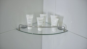 Uma prateleira no banheiro com três frascos de produtos de bem-estar e spa TERRANEA.