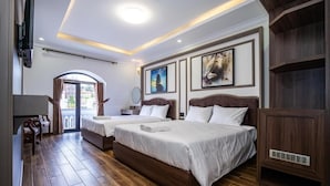 Quarto de hotel com duas camas, piso de madeira, televisão e obras de arte nas paredes.