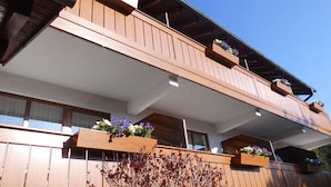 Um edifício de vários andares com varandas, cada uma adornada com grades de madeira e caixas de flores.