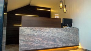 Uma receção com bancada de mármore, painéis de madeira e iluminação pendente.