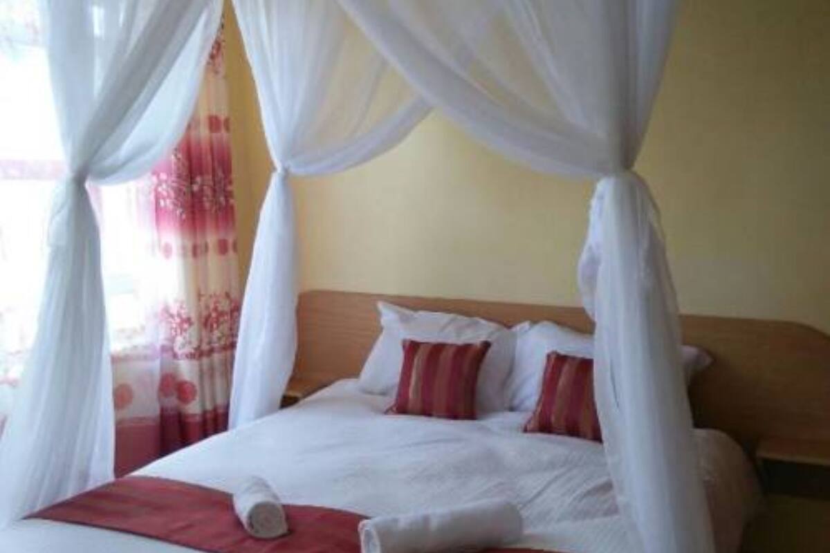 Quarto de hotel com cama, cortinas brancas e janela com cortinas florais.