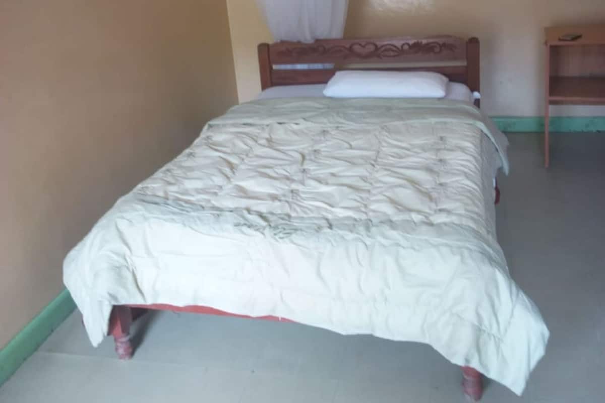 Quarto com cama, mesa de cabeceira, cadeira e mosquiteiro.