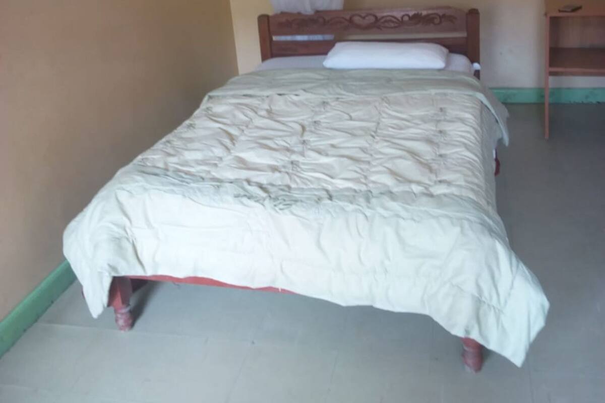 Quarto com cama, mesa de cabeceira e mosquiteiro.