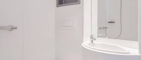 Uma casa de banho moderna com sanita, lavatório e chuveiro.