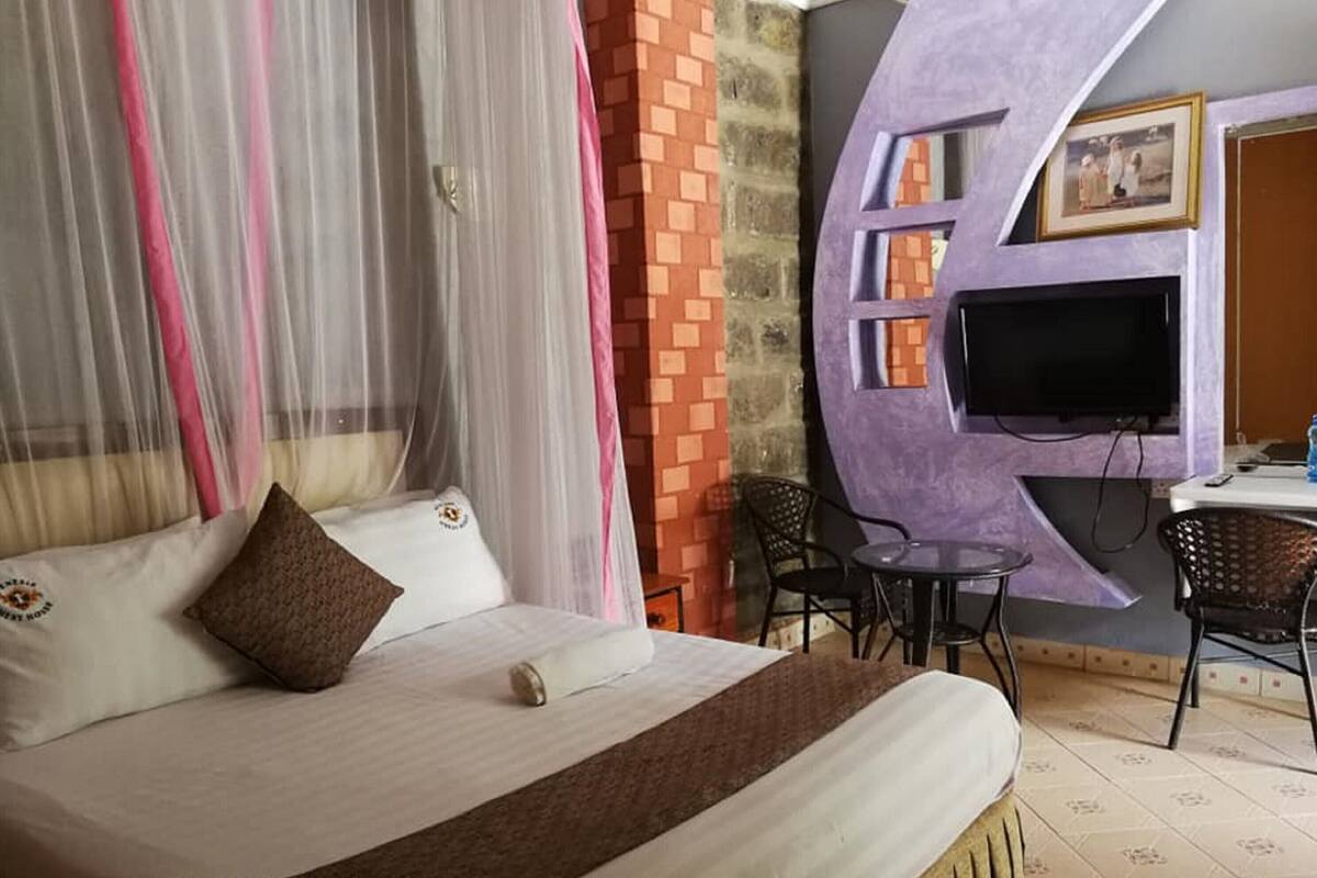 Quarto com cama, televisão e uma pequena mesa com cadeiras.
