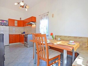 Uma cozinha compacta com armários de madeira, uma mesa de jantar com cadeiras e um forno pequeno.