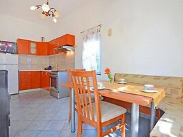Uma cozinha compacta com armários de madeira, uma mesa de jantar com cadeiras e um forno pequeno.