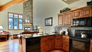Cozinha com armários de madeira, fogão embutido e uma grande ilha com pia.