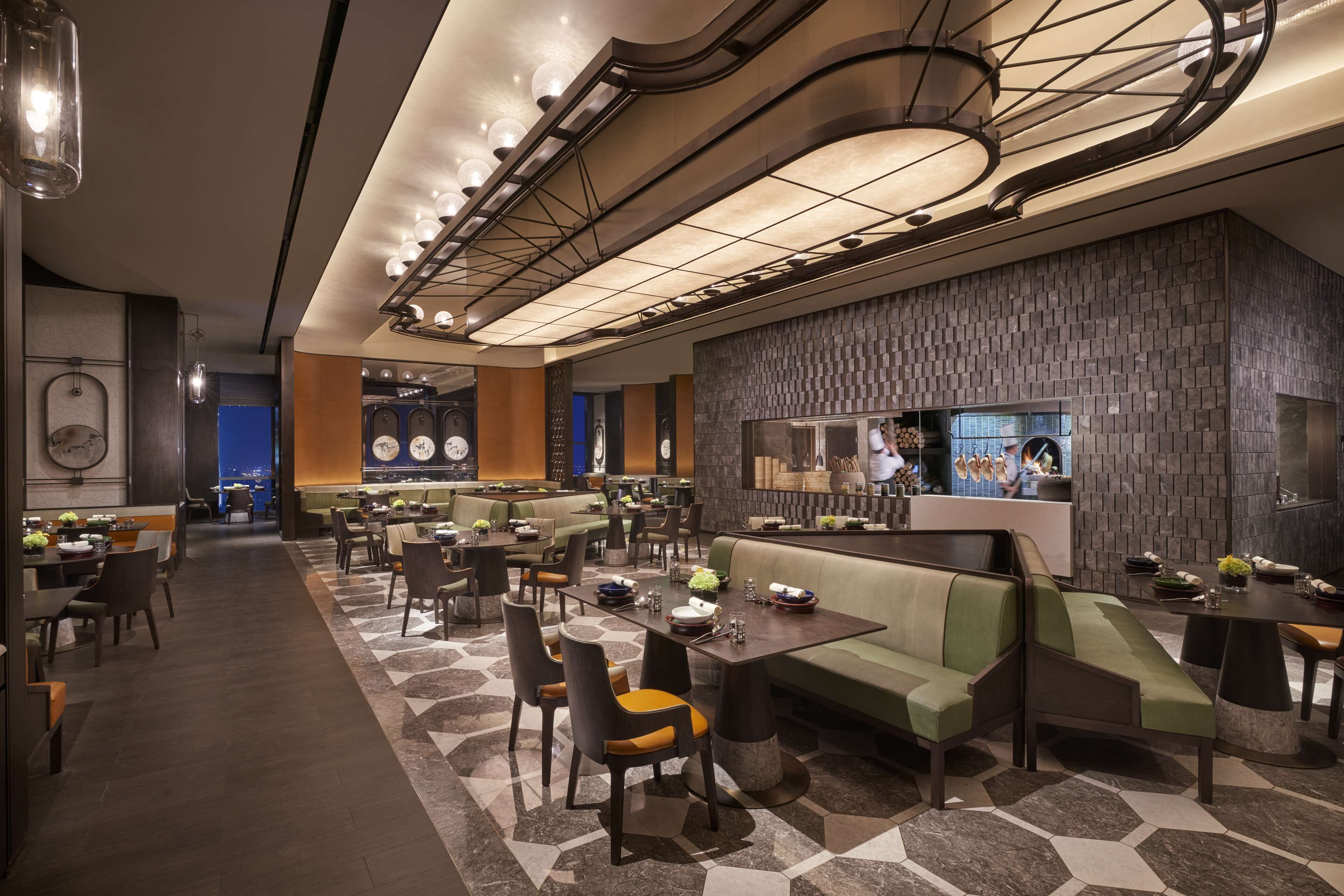 Um restaurante moderno com chão xadrez, assentos acolchoados verdes e parede estampada.