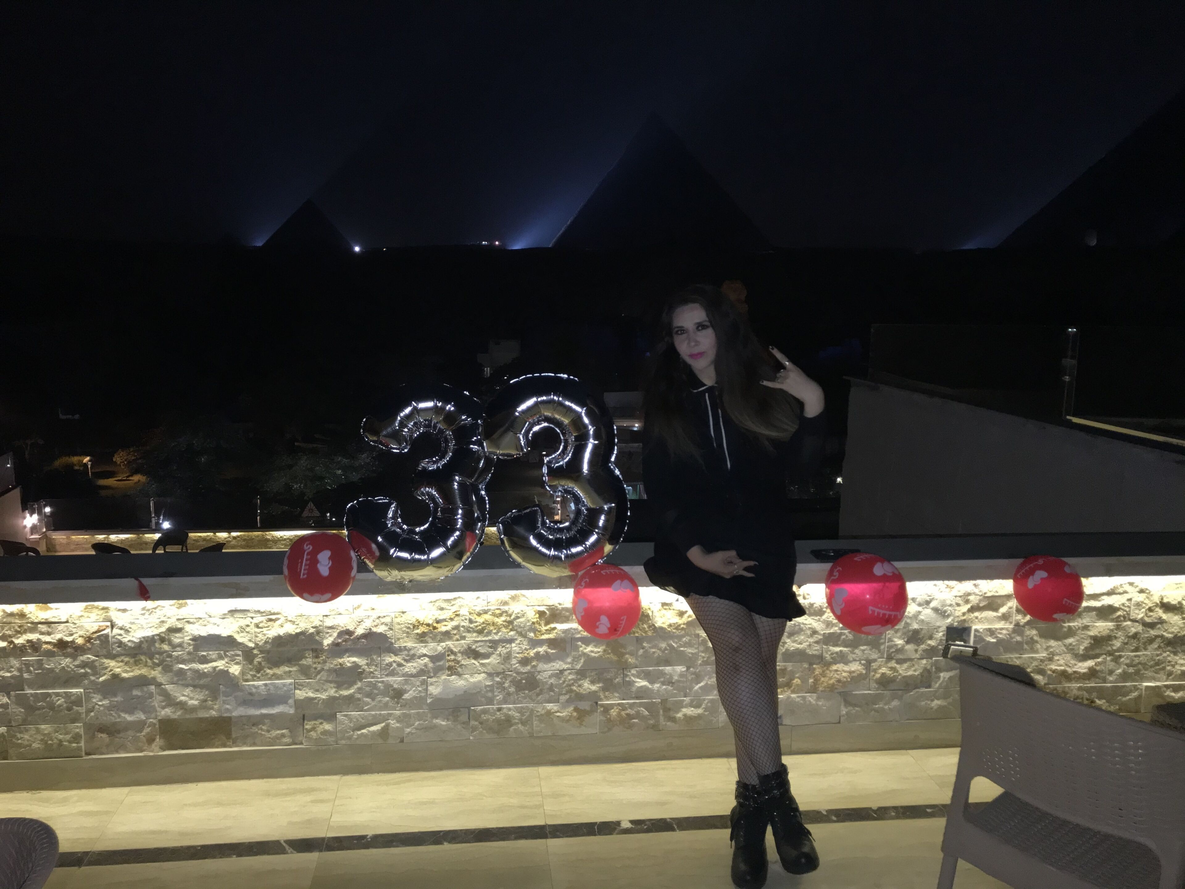 Uma pessoa em frente a uma parede de pedra com o número '33' iluminado.