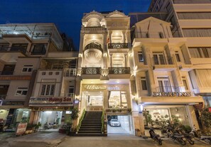 Um hotel com entrada imponente, vários andares e fachada bem iluminada.