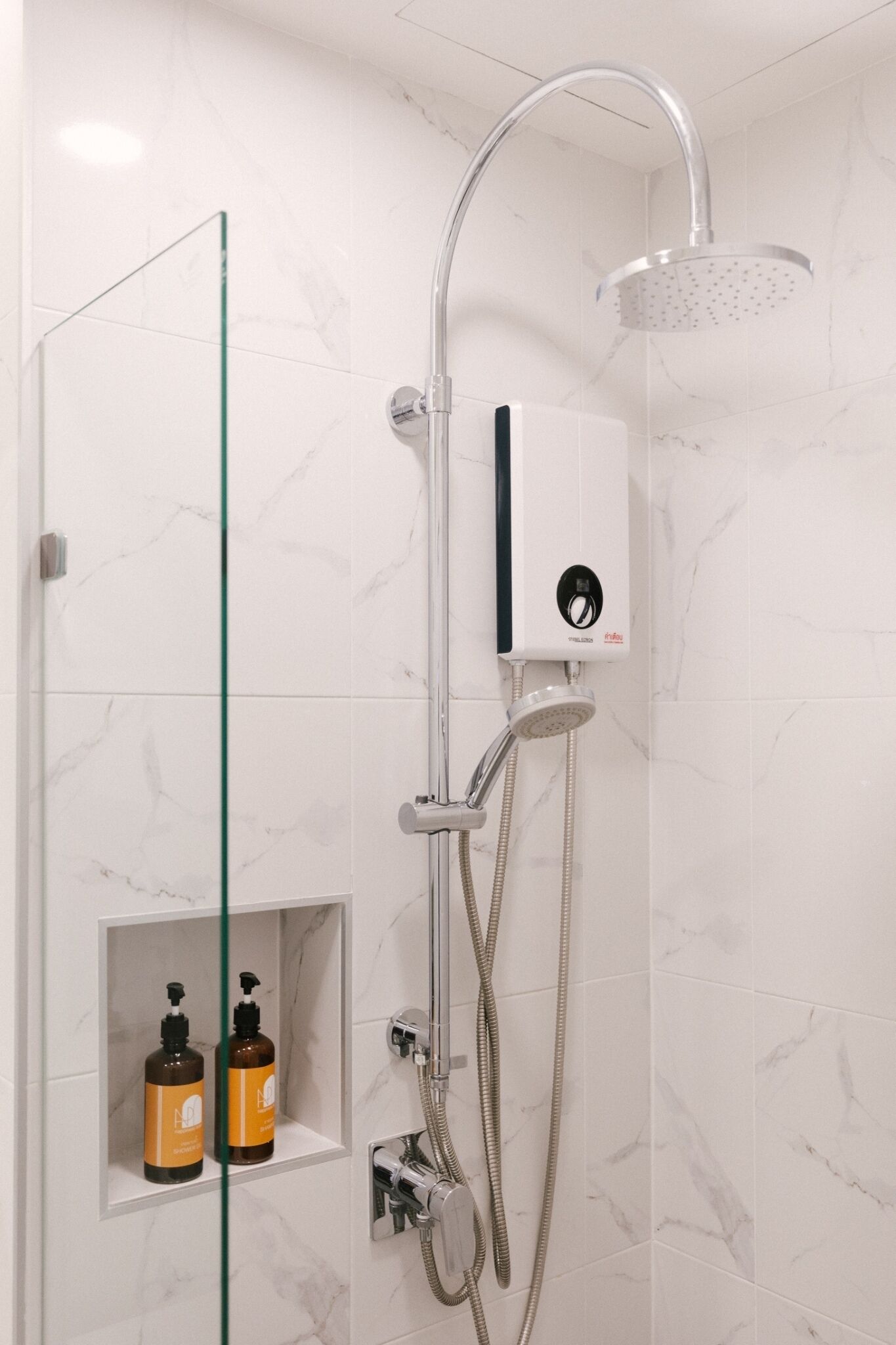 Chuveiro moderno com porta de vidro, chuveiro manual e painel de controle fixado na parede.