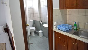 Casa de banho com sanita, lavatório e cesto azul para roupa.