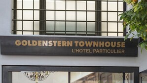 A entrada do hotel Goldenstern Townhouse, com uma área de recepção, um candelabro e um mural de mapa na parede.