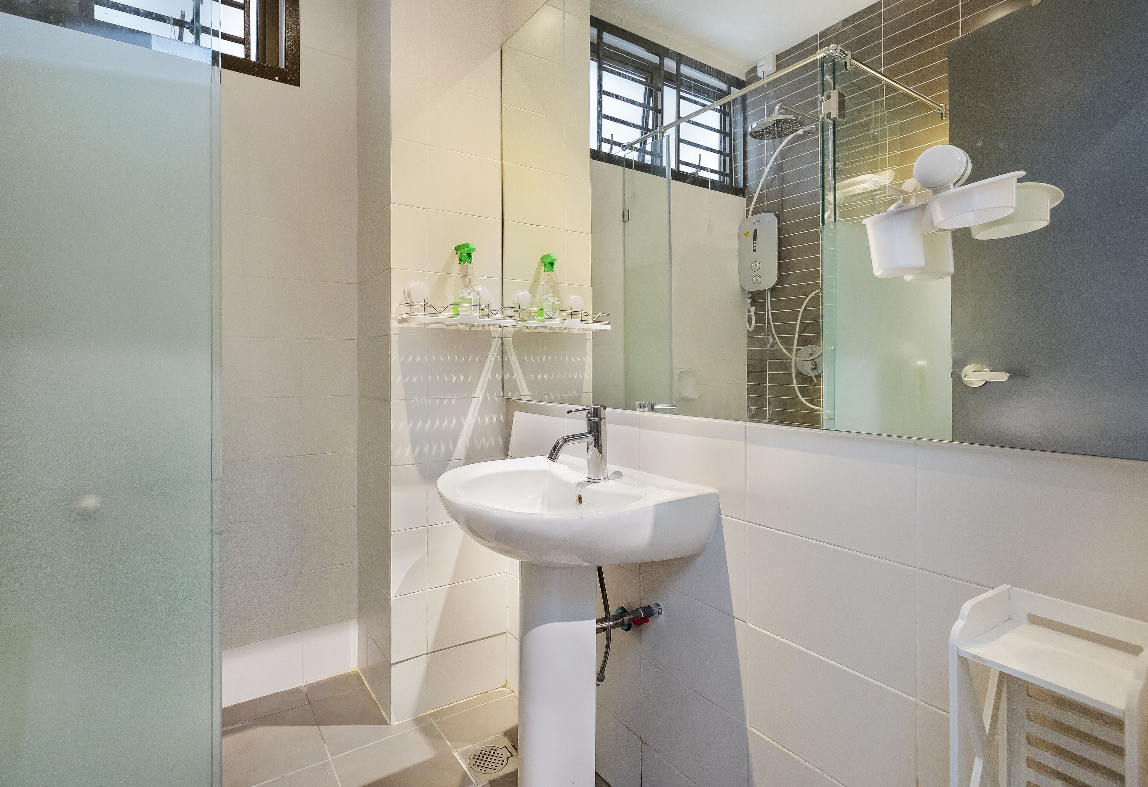 Casa de banho moderna com lavatório branco, cabine de duche em vidro e espelho com moldura preta.