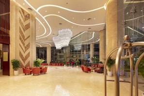Um hall amplo com um lustre moderno, áreas de estar confortáveis e entrada de vidro.