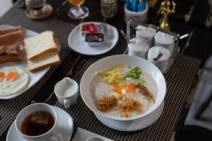 Mesa de café da manhã com mingau, torradas, ovos e uma xícara de chá.