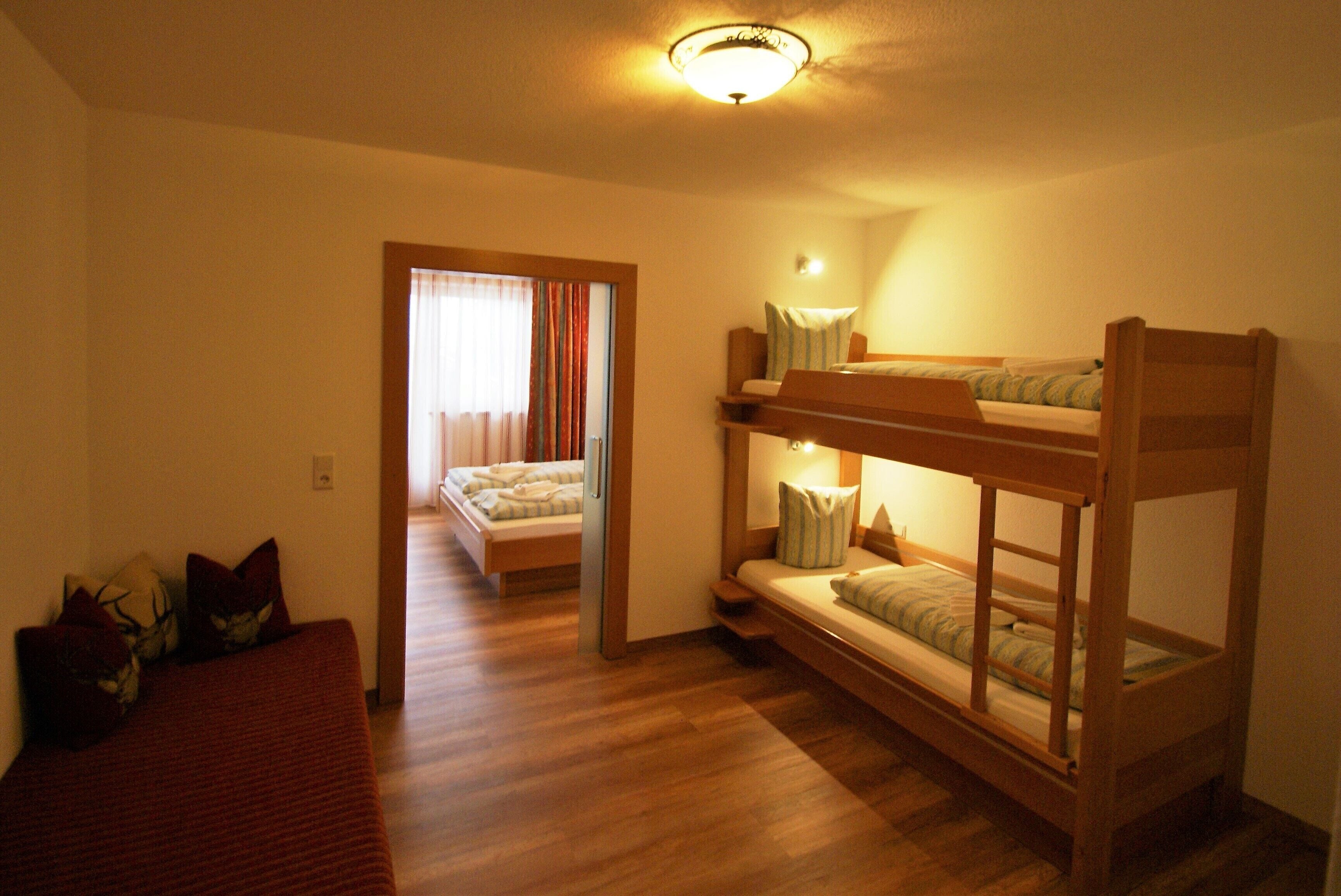 Um quarto com uma cama de solteiro, um sofá e um corredor que dá para outro quarto.