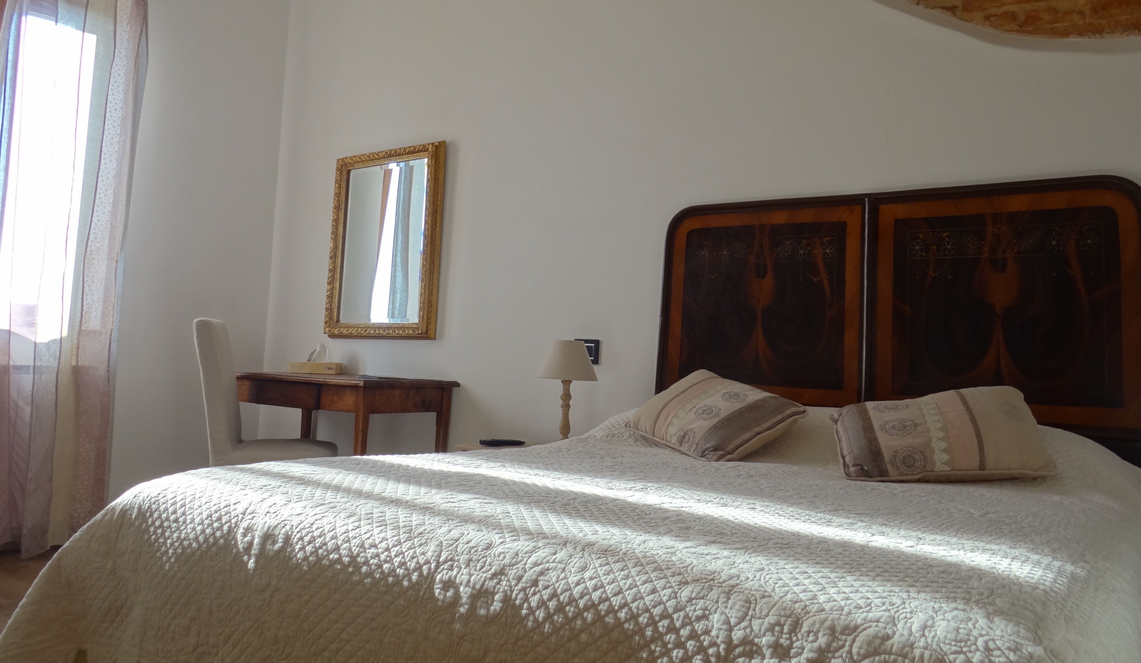 Quarto com cama, escrivaninha, cadeira, abajur e espelho.