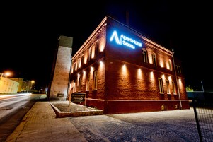 Edifício de tijolos com letreiros iluminados para 'ApartHotel Sorau' e placa de estacionamento.