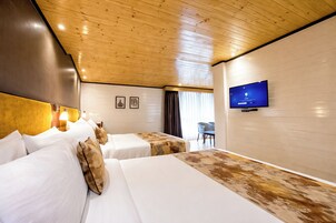 Quarto de hotel com duas camas, televisão e teto de madeira.