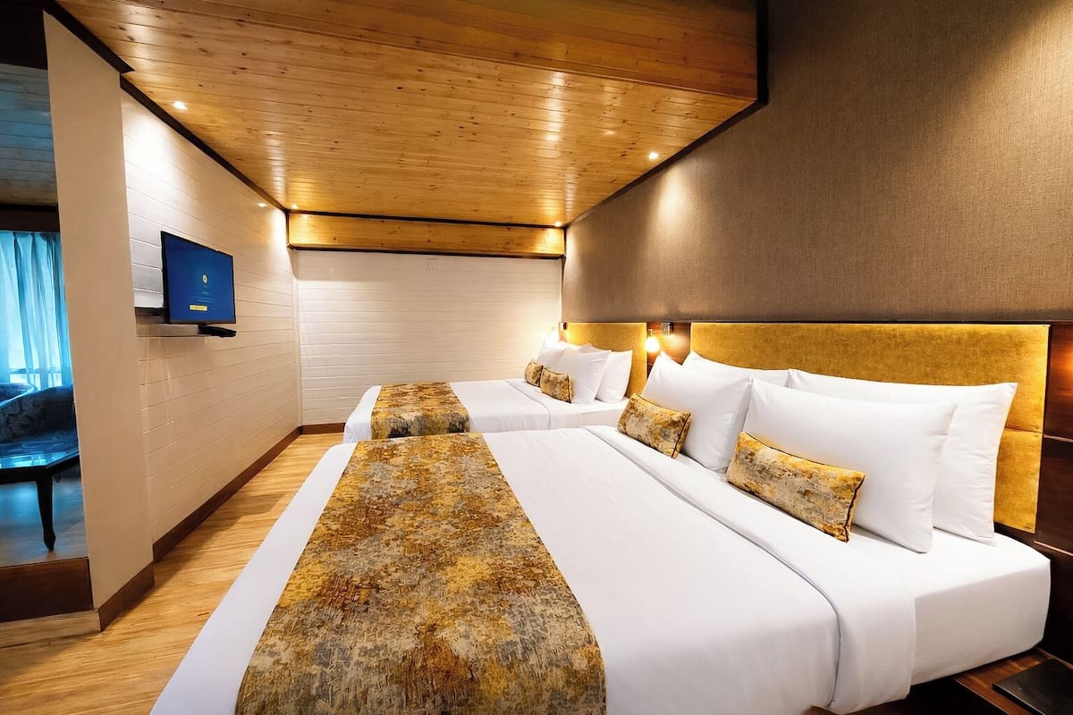 Quarto de hotel com uma cama grande, televisão e teto de madeira.