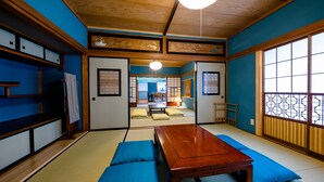 Um quarto japonês tradicional com tatames, uma mesa de madeira e almofadas azuis.